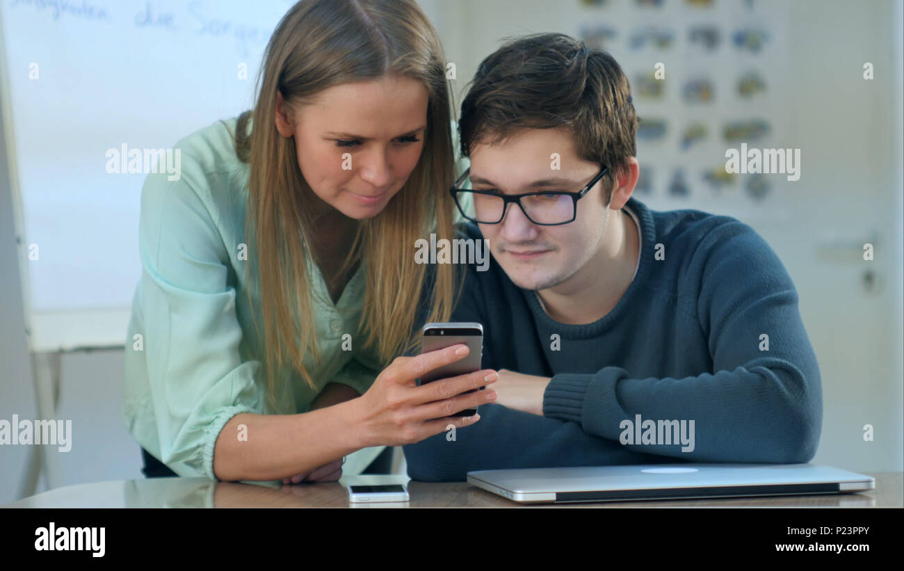 Two young students using phone during class Stock Photo - Alamy