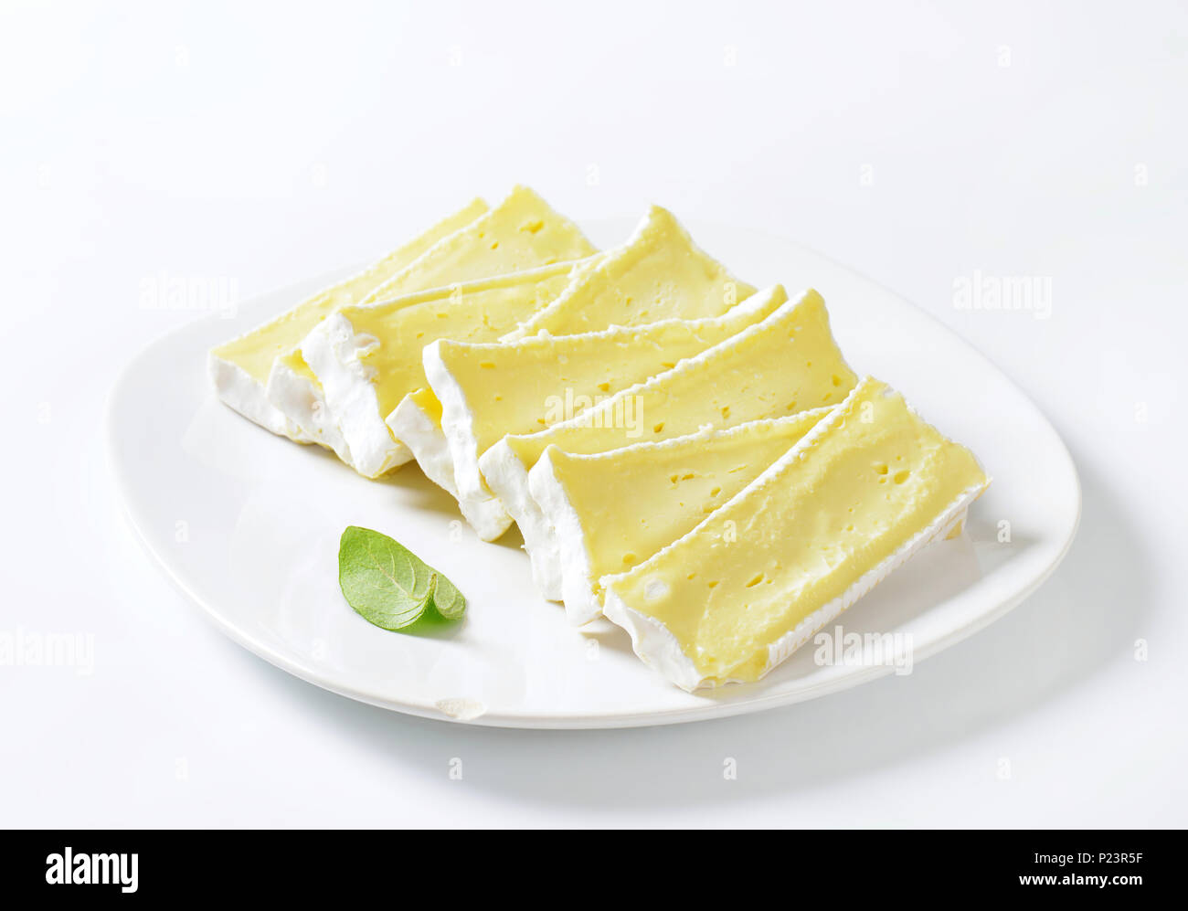 plate of sliced soft cheese with white rind on white background Stock ...
