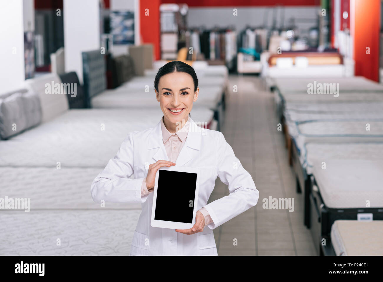 smiling shop assistant in white coat showing tablet with blank screen ...