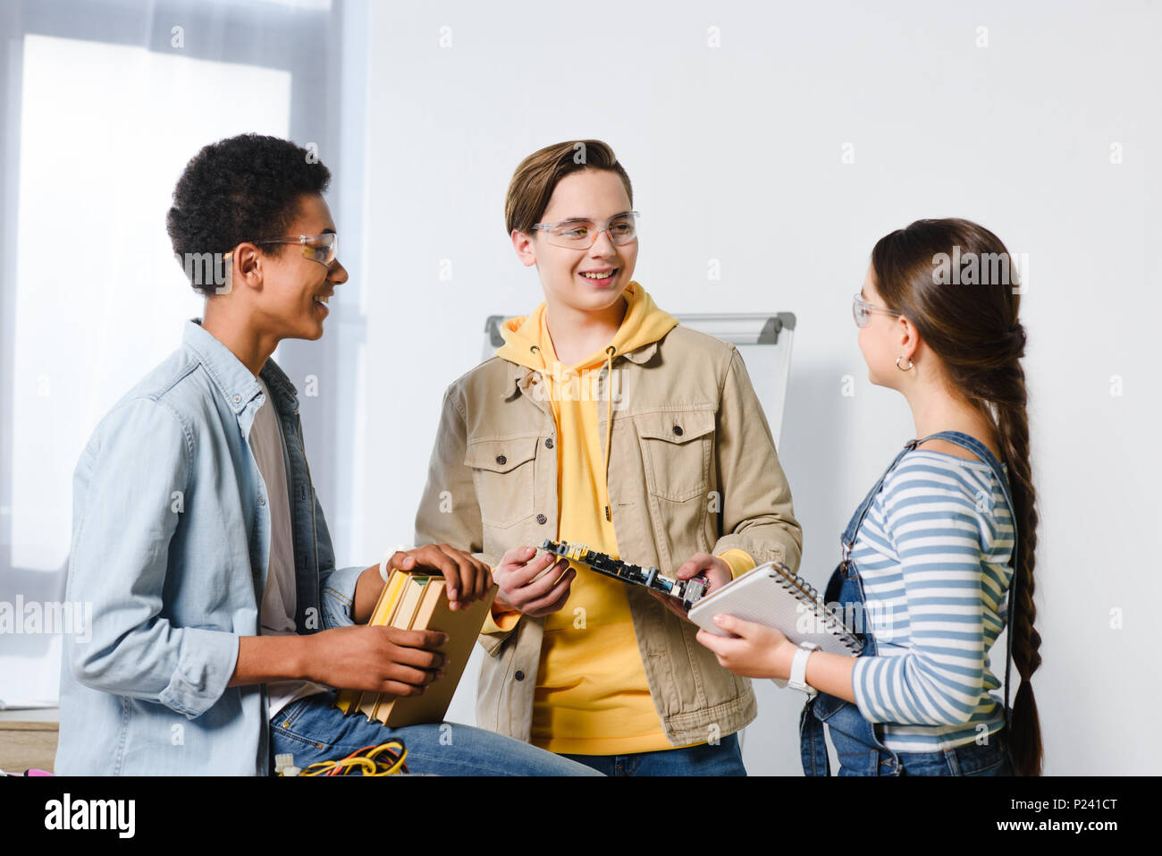 multicultural teenagers with computer circuit and books at home Stock ...
