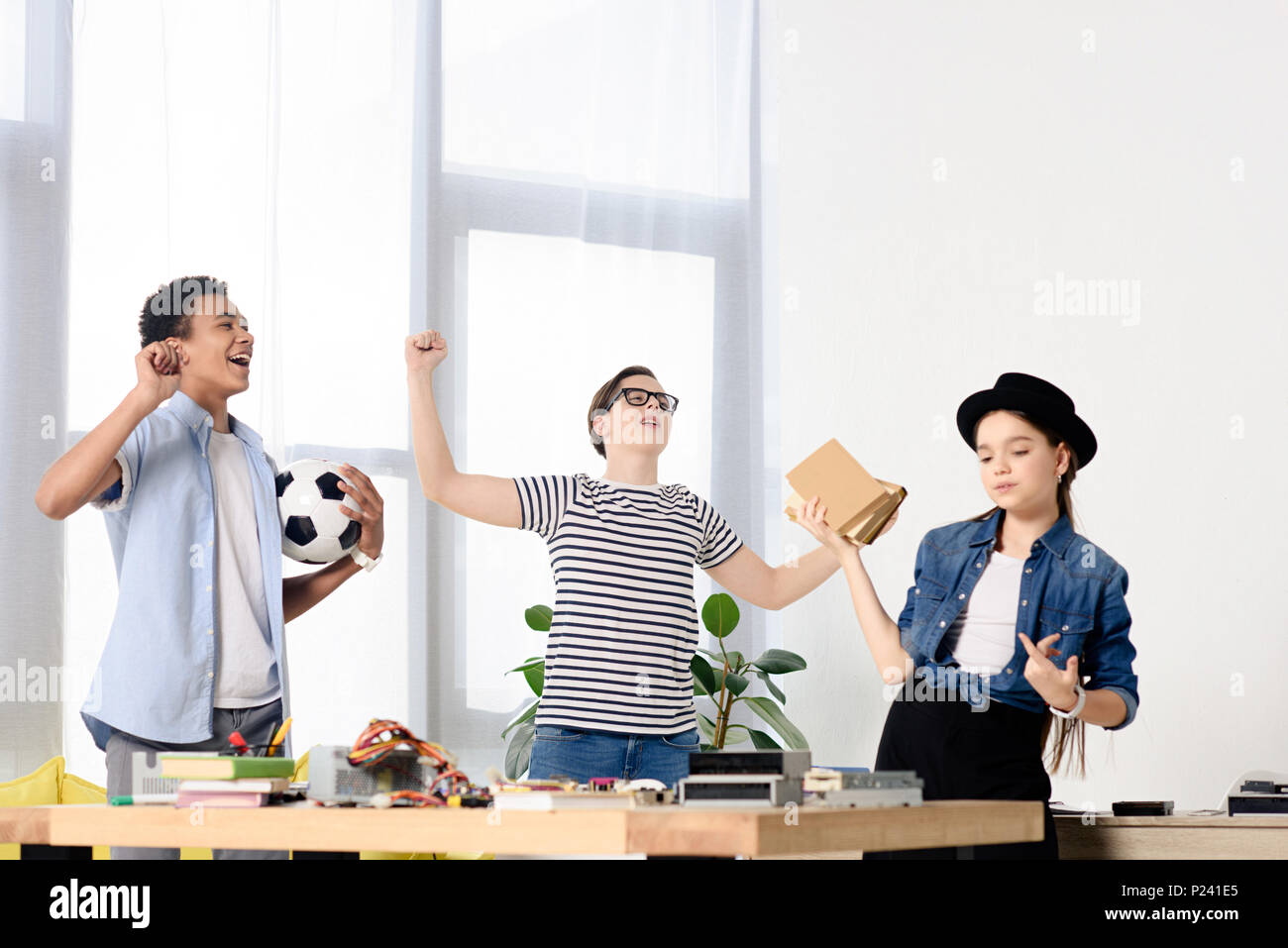 multicultural teenagers showing yes gestures and holding football ball ...