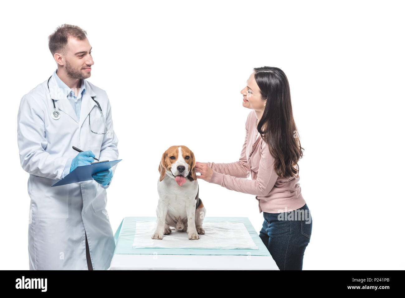 smiling young woman with beagle and veterinarian writing in clipboard ...