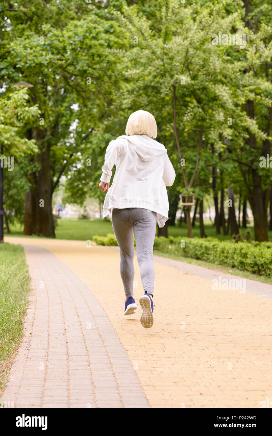 back view of sportive woman with grey hair jogging in park Stock Photo ...