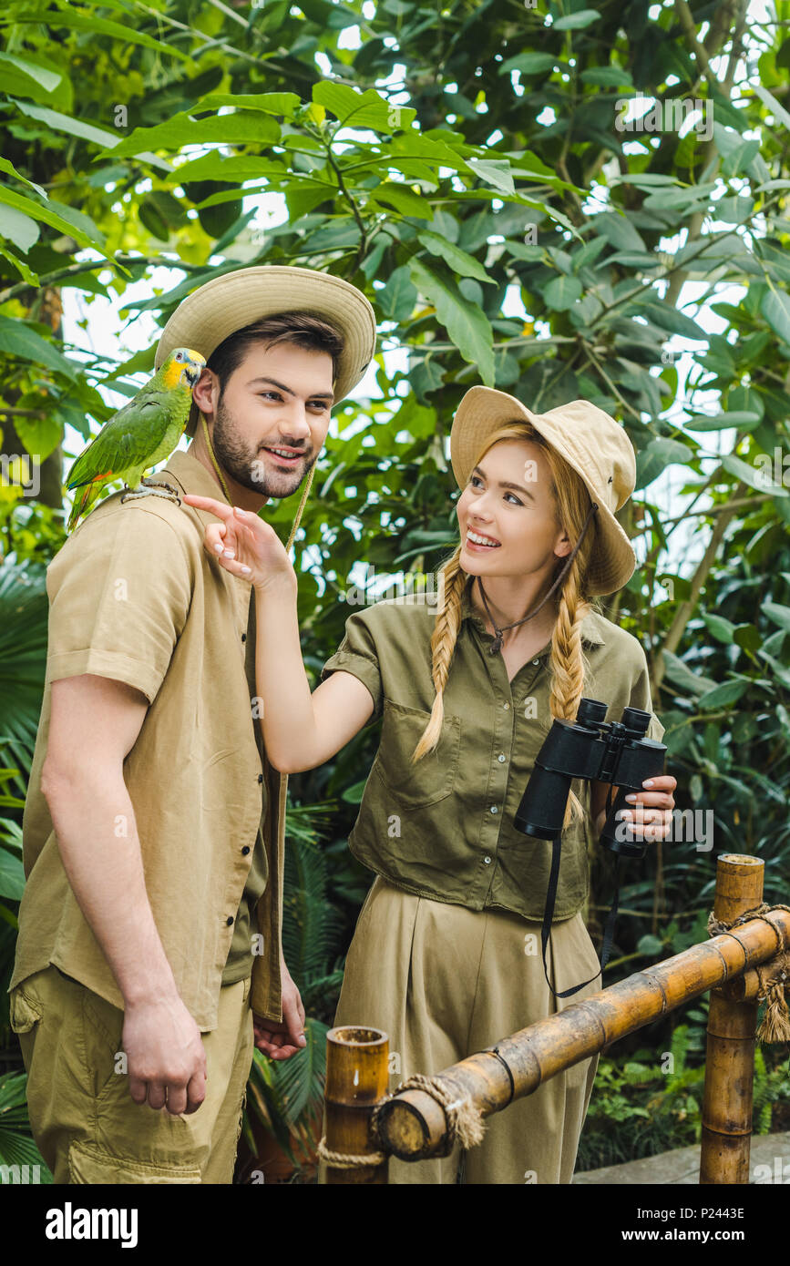 attractive young couple in safari suits with binoculars hiking together ...