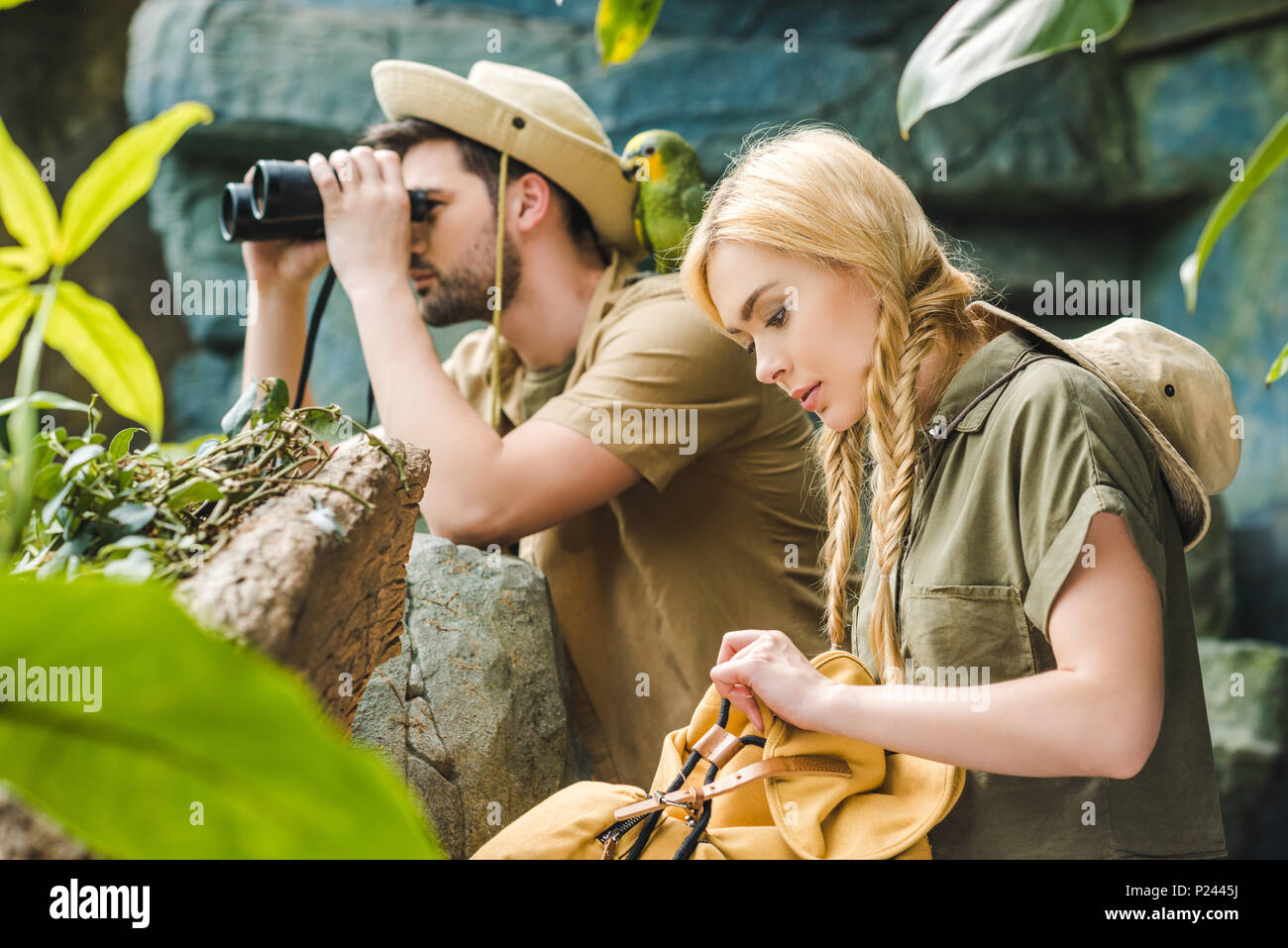 active young couple in safari suits with parrot hiking in jungle Stock ...