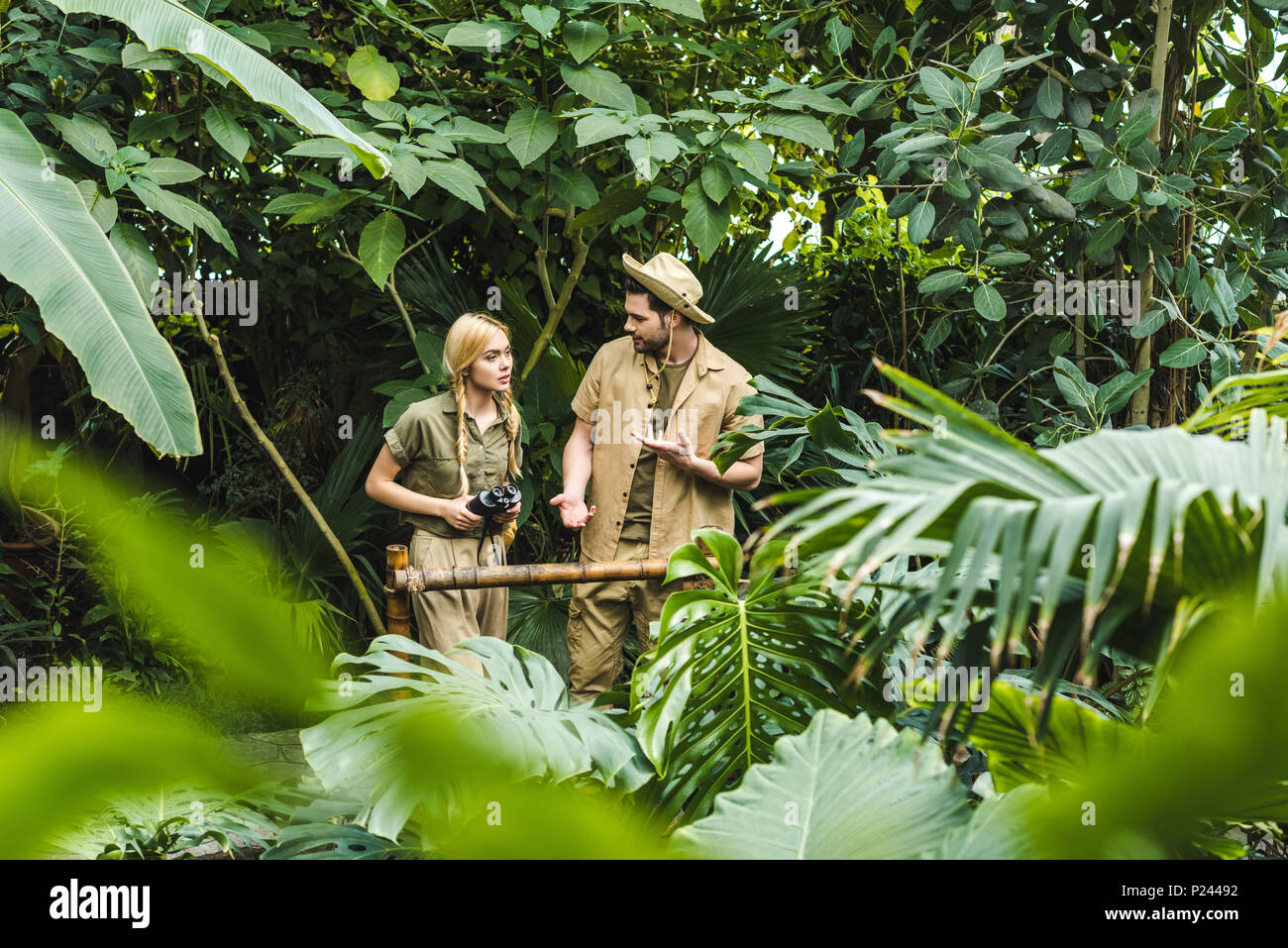 attractive young couple in safari suits holding hands and hiking in ...