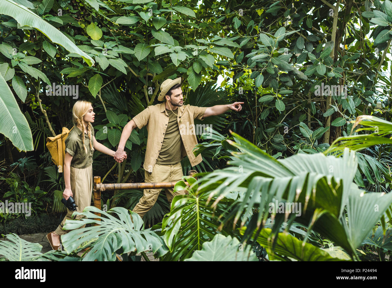 beautiful young couple in safari suits holding hands and hiking in ...