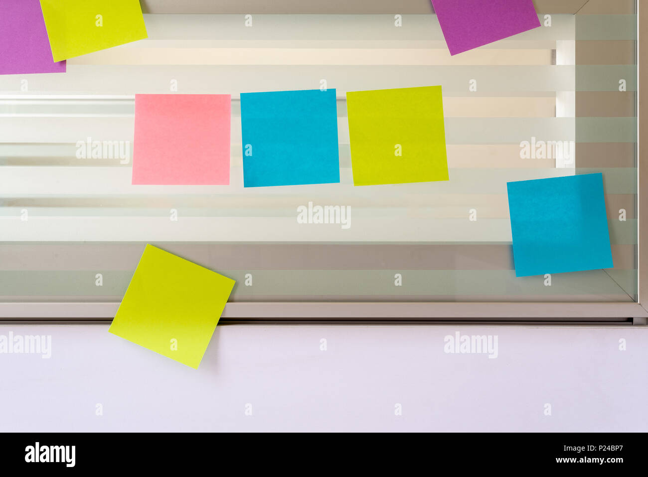 Randomly scattered colored sticky notes over glass screen of a bench ...