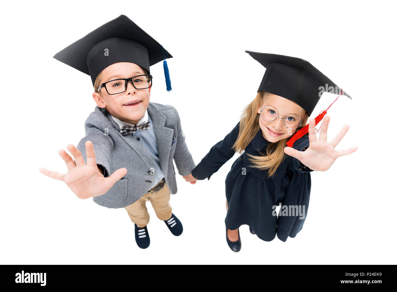 top view of pupils in graduation hats outstretching hands at camera ...