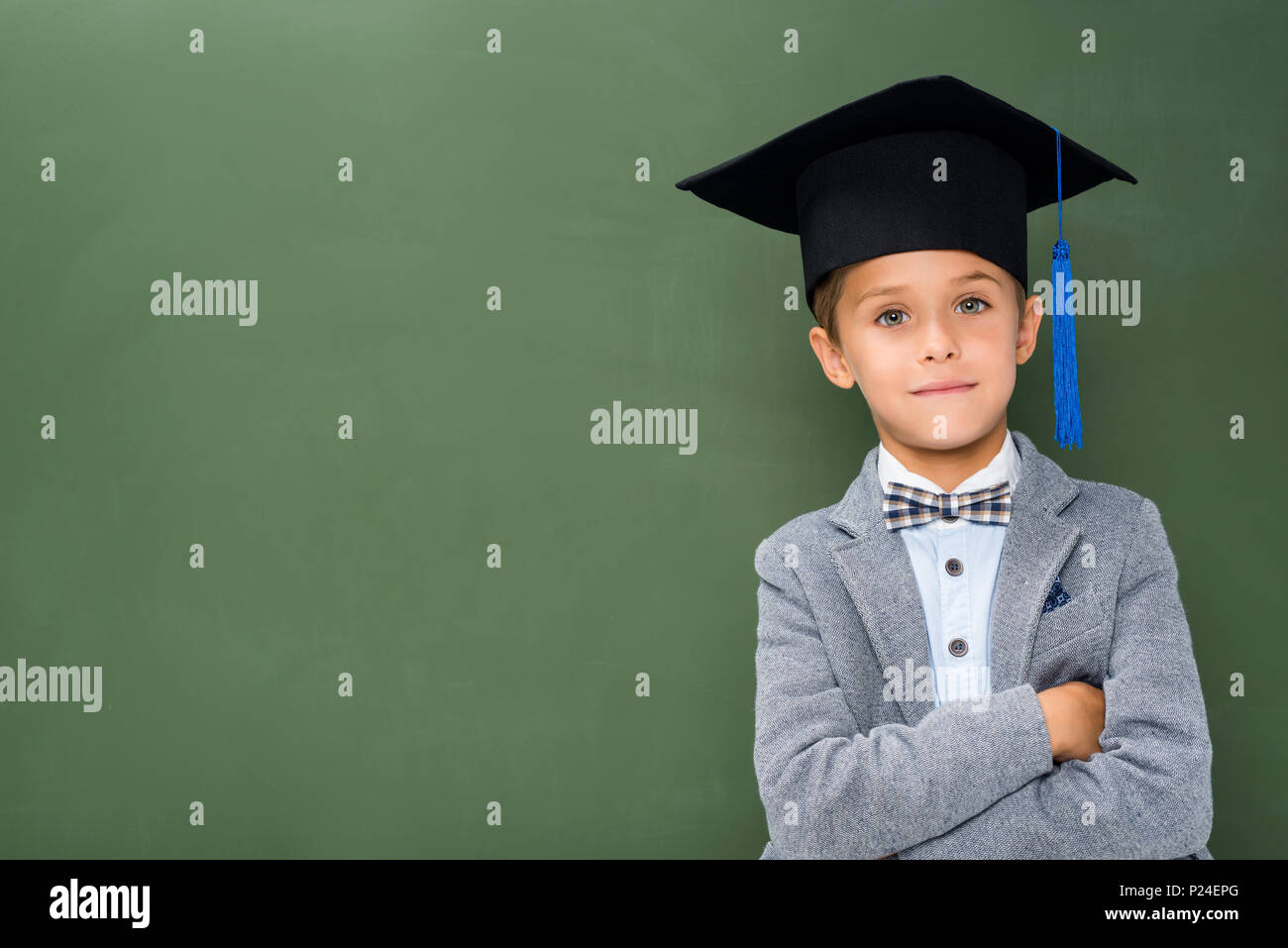 schoolboy in graduation hat with crossed arms next to chalkboard Stock ...
