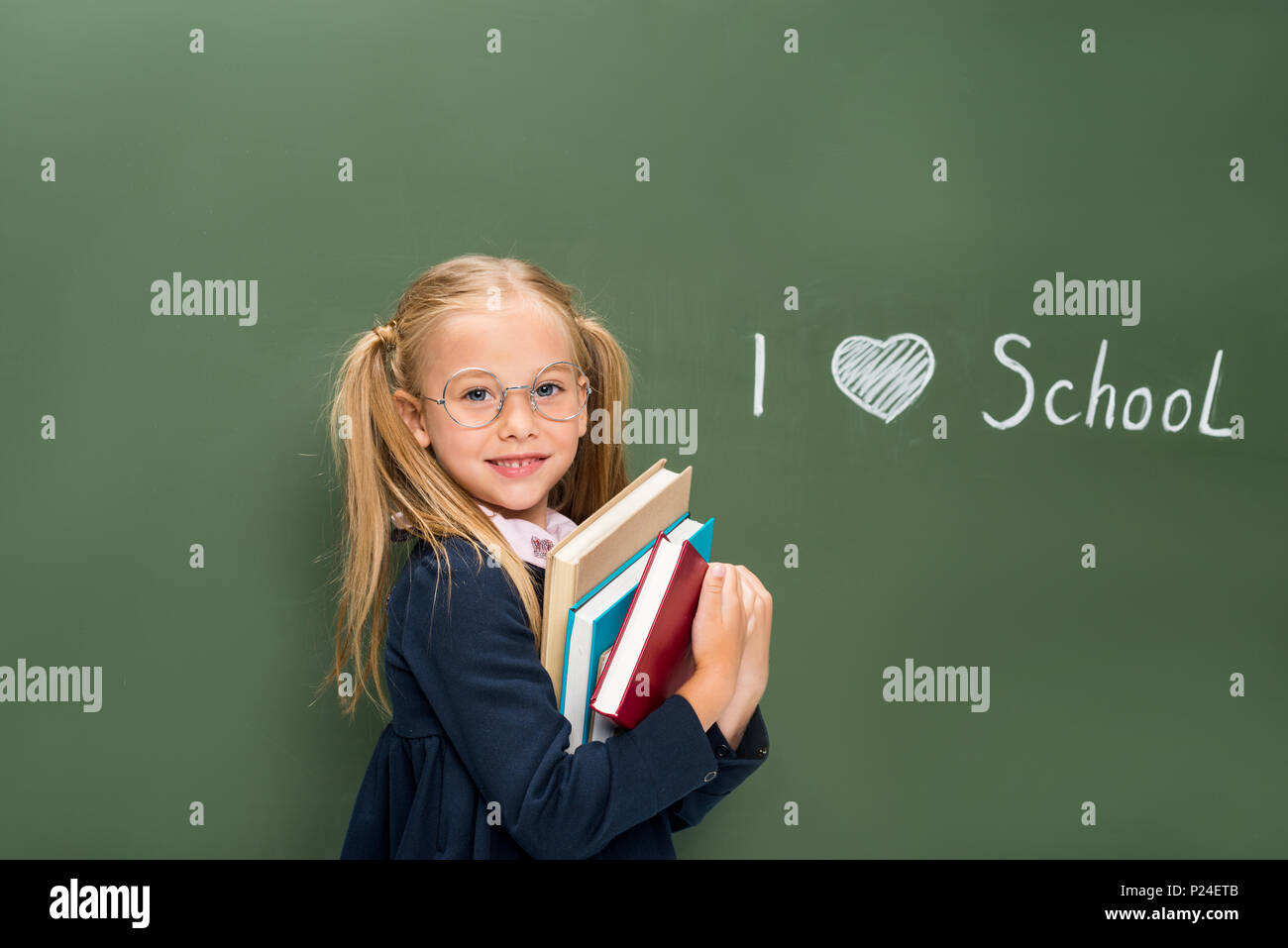 schoolgirl with pile of books next to chalkboard with i love school ...