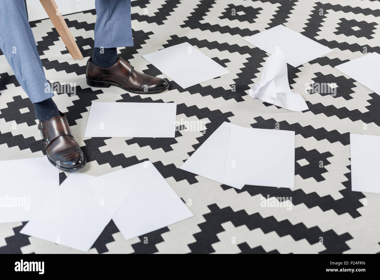 partial view of businessman legs and empty papers on floor in office ...