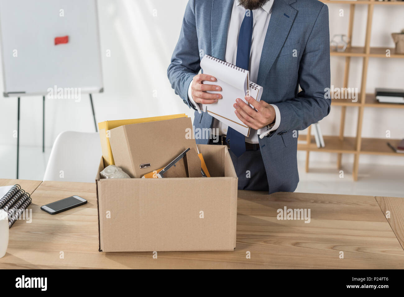 cropped shot of fired businessman packing office supplies in cardboard ...