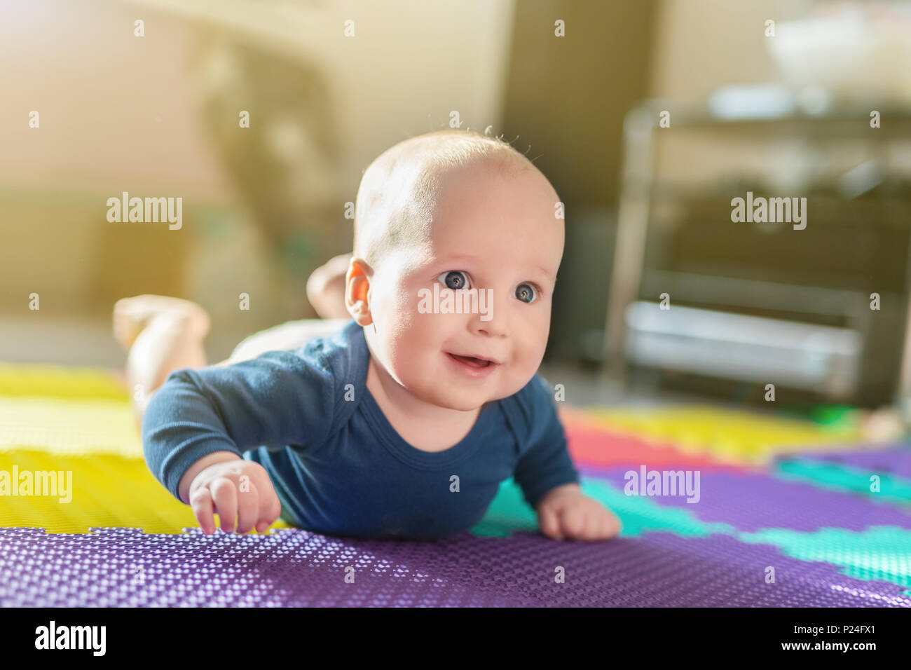 Portrait of cute caucasian baby boy crawling on soft playing mat ...
