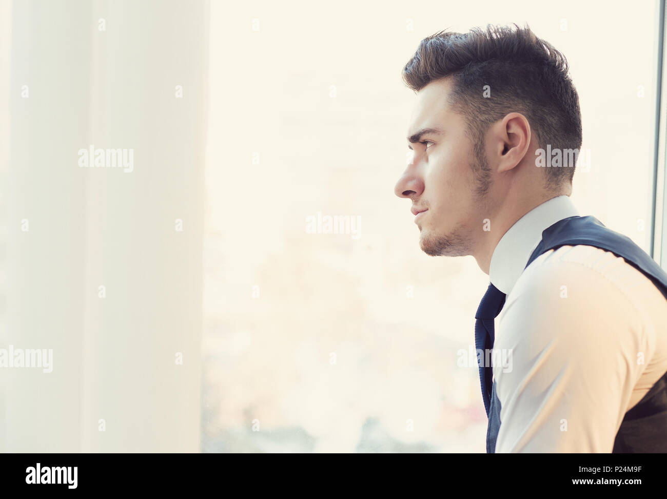 Side view of preoccupied young man looking away in window with feeling ...
