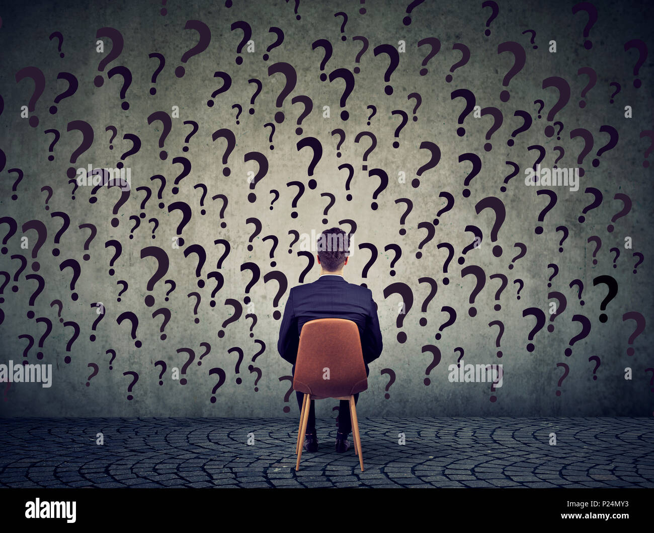 Young business man sitting on a chair in front of a wall has many ...