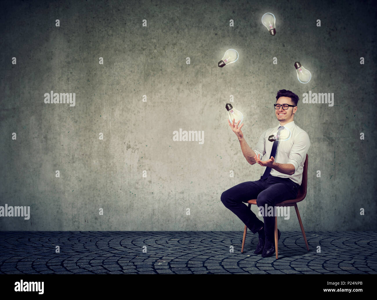 Happy smart man sitting on chair against gray concrete wall and ...