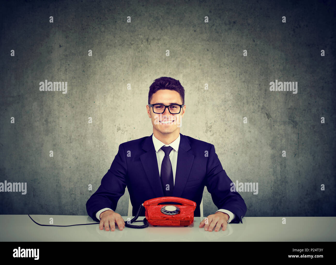 Handsome business man sitting at desk with vintage land line telephone ...