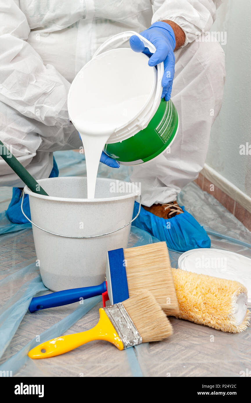 House painter at work pours white paint into a container Stock Photo ...