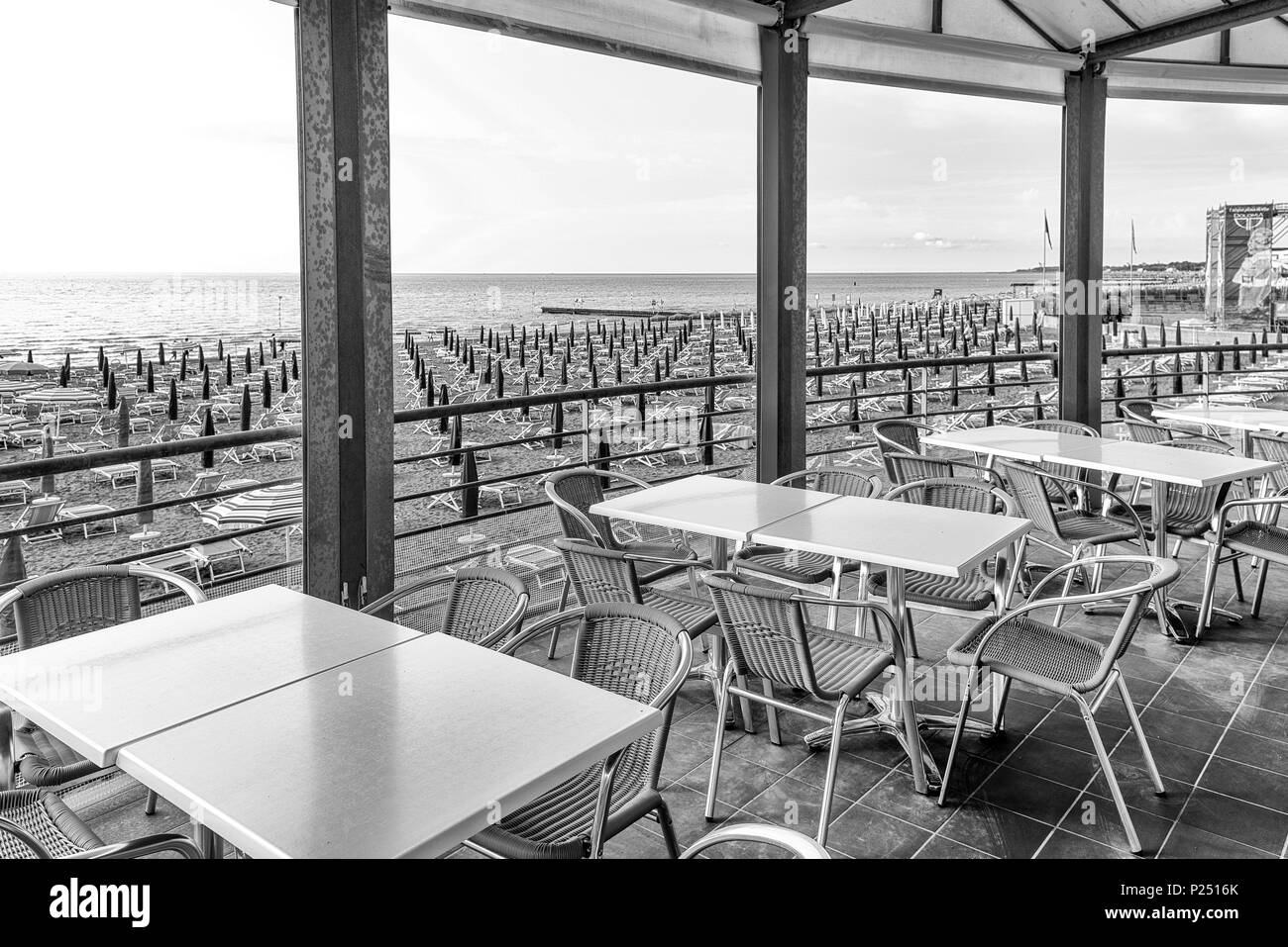 Chairs and tables in a beach bar with view to the sea, architecture on ...