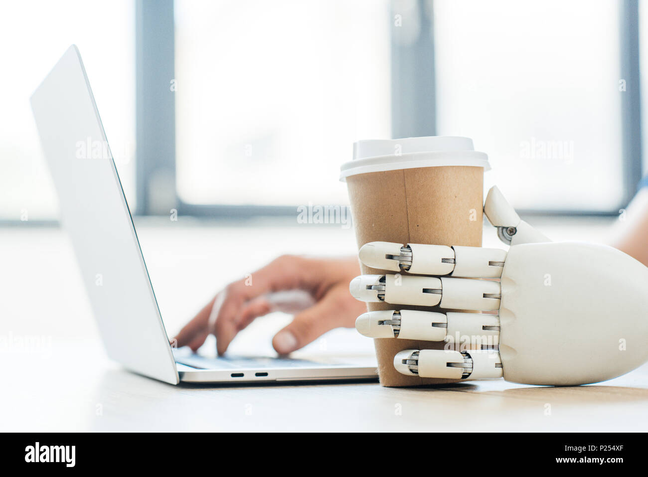 close-up view of robotic arm holding disposable coffee cup and human ...
