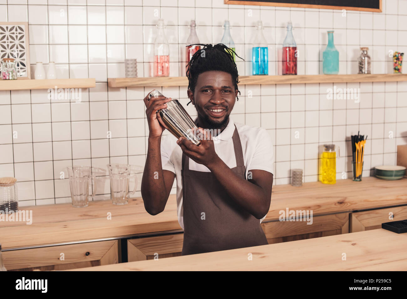 african american bartender making cocktail in shaker at bar counter ...