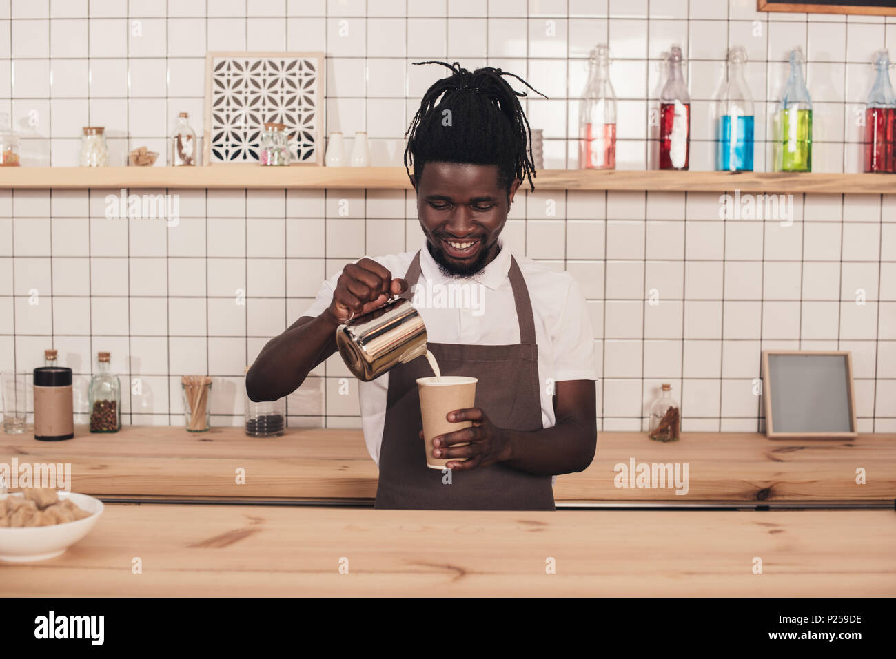 african american barista making coffee in disposable cup at bar counter ...
