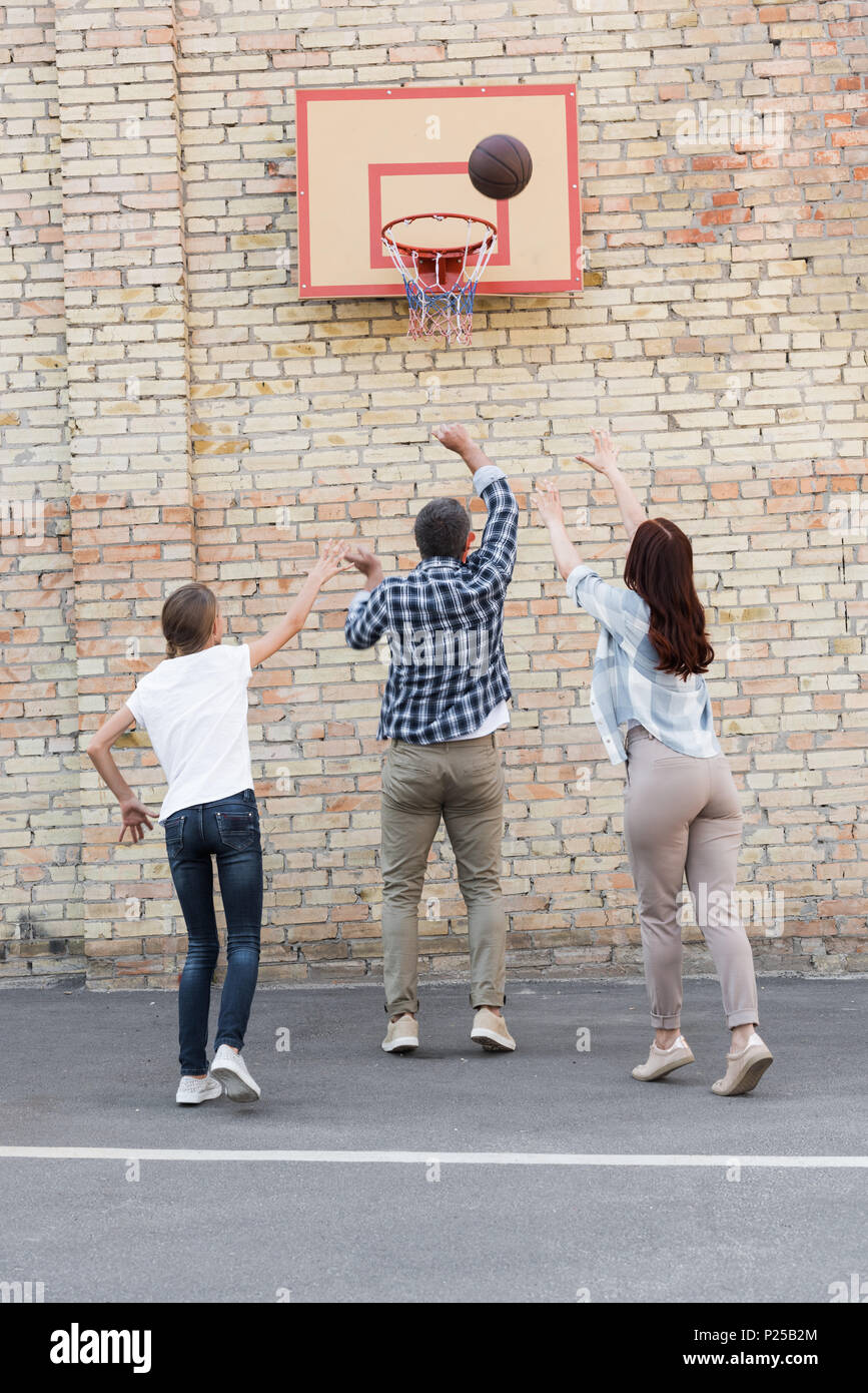 rear view of family playing basketball together on playground Stock ...