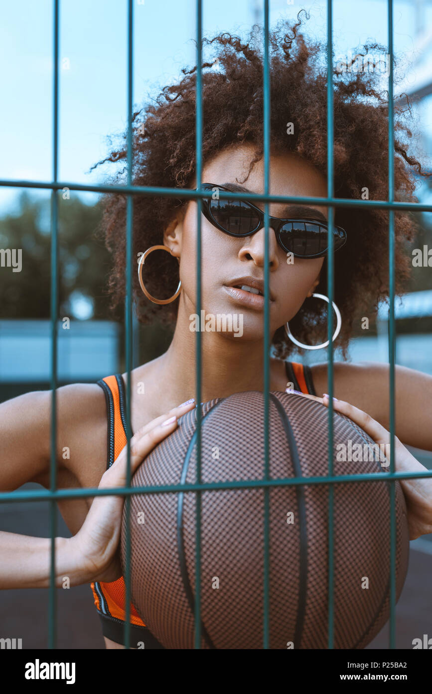 young african-american woman in sports bra and sunglasses holding a ...