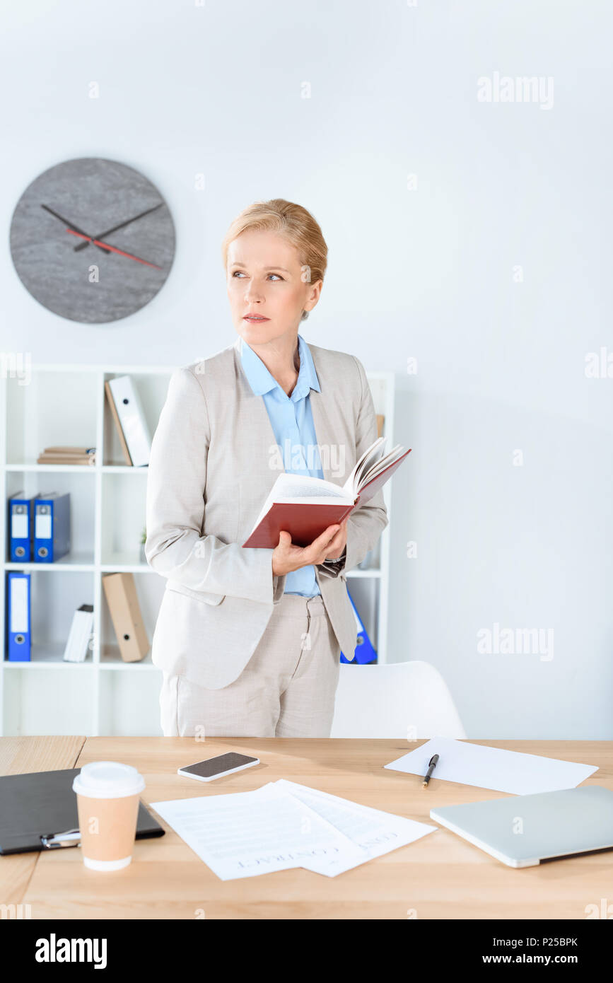 mature businesswoman reading book in office Stock Photo - Alamy