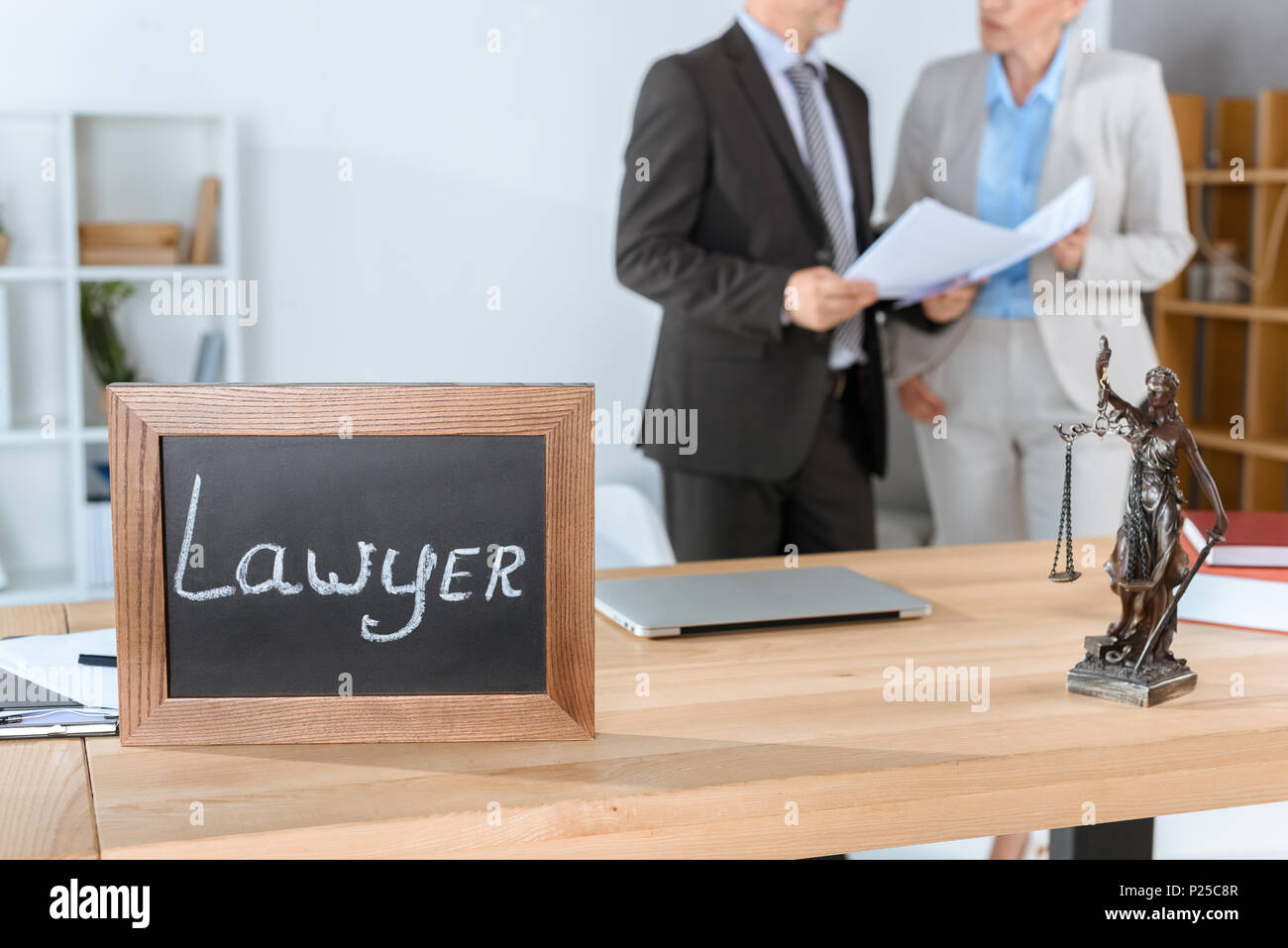 lawyer workplace with themis sculpture and blurred partners on ...