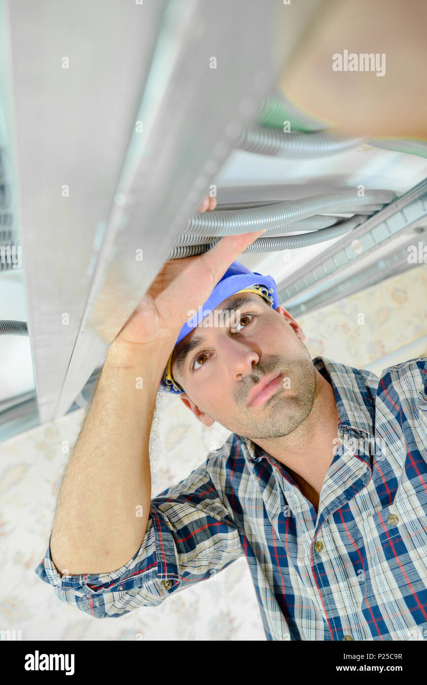 Man looking at cables above ceiling Stock Photo - Alamy