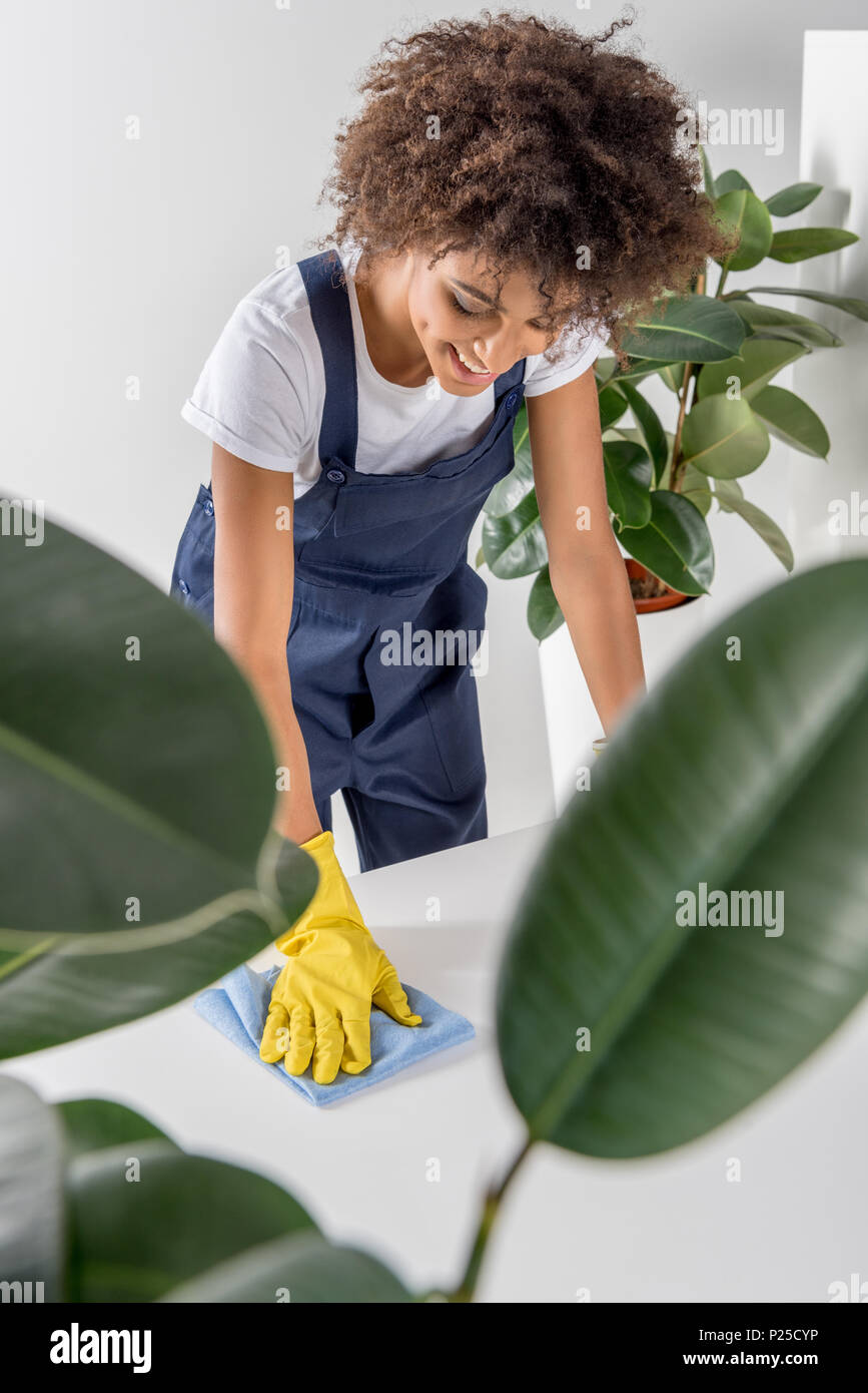 smiling young african american housekeeper wiping table with rag Stock ...