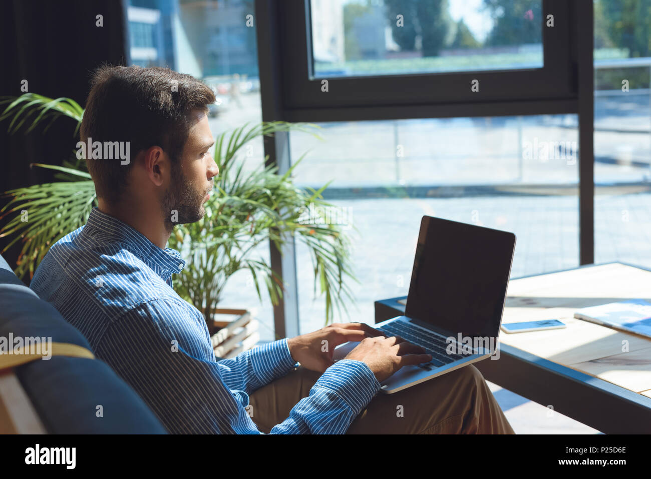 serious young man using laptop with blank screen in cafe Stock Photo ...