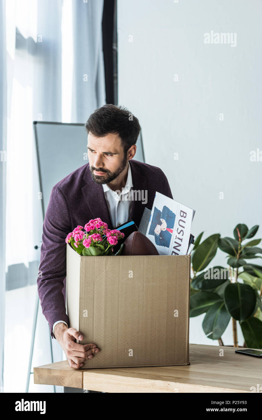 dismissed businessman taking box of personal stuff from desk at office ...