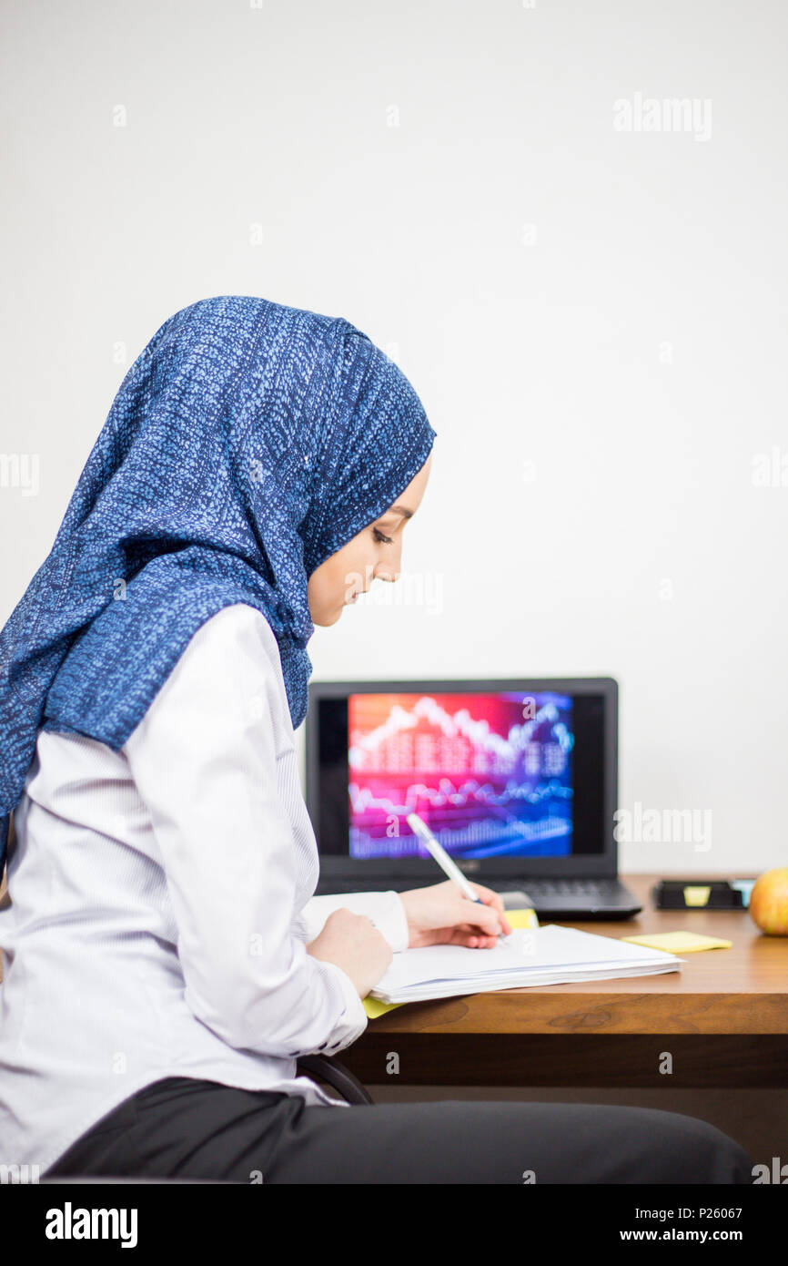 Covered young Muslim with hijab, in office, business and finance ...