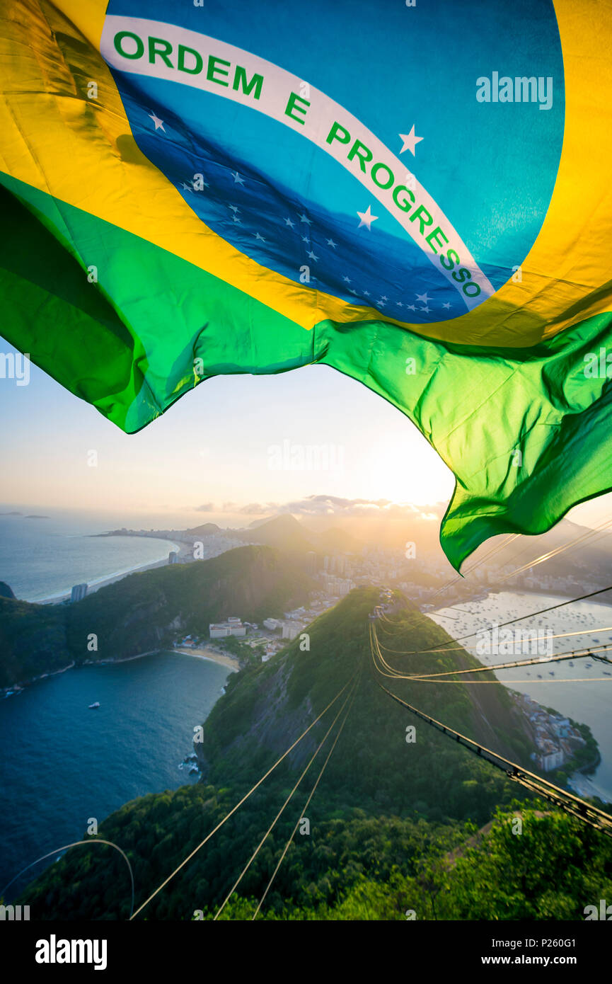 Brazilian flag shines above the golden sunset city skyline at Sugarloaf ...