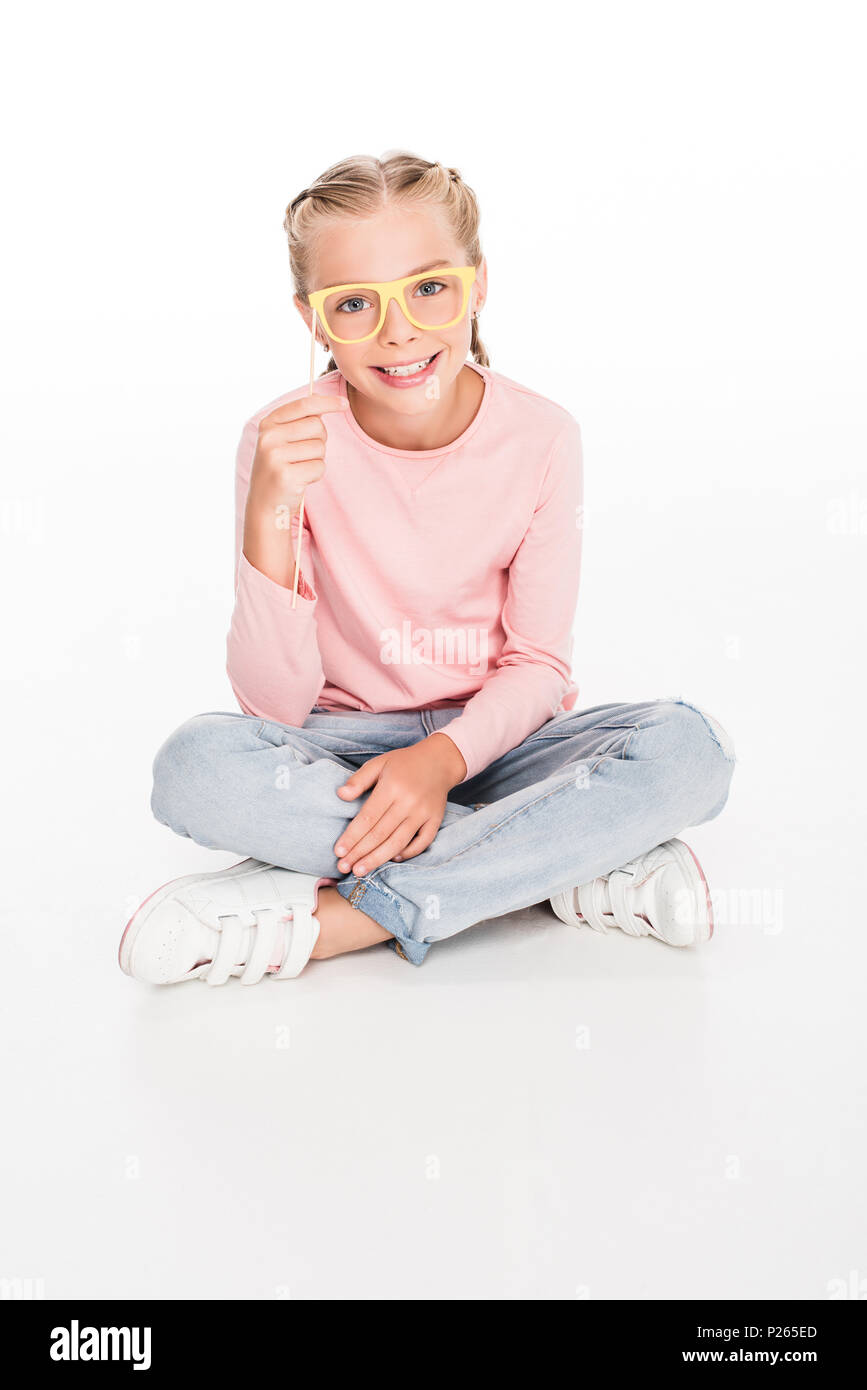 Cheerful child sitting on floor with legs crossed and playing with ...