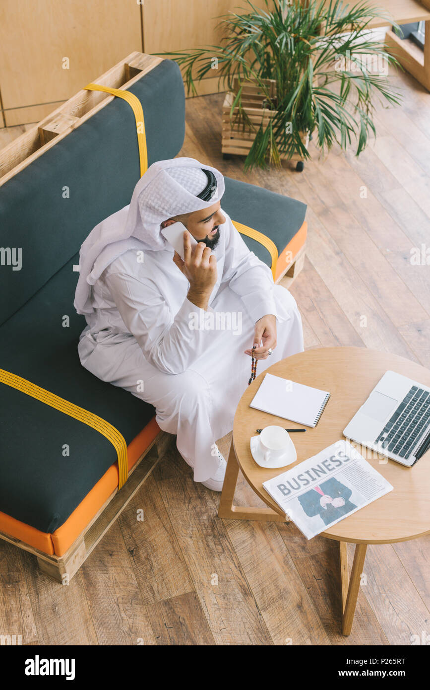 top view of muslim businessman talking by phone while sitting on sofa ...