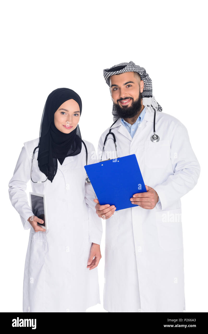 happy muslim doctors in coats isolated on while looking at camera and ...