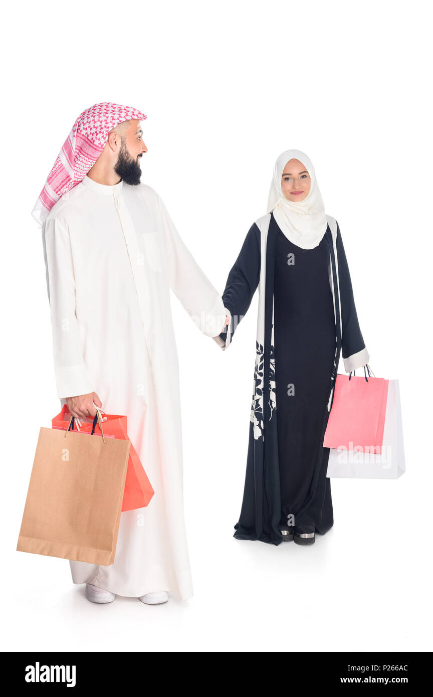 muslim couple in traditional clothing with shopping bags isolated on ...