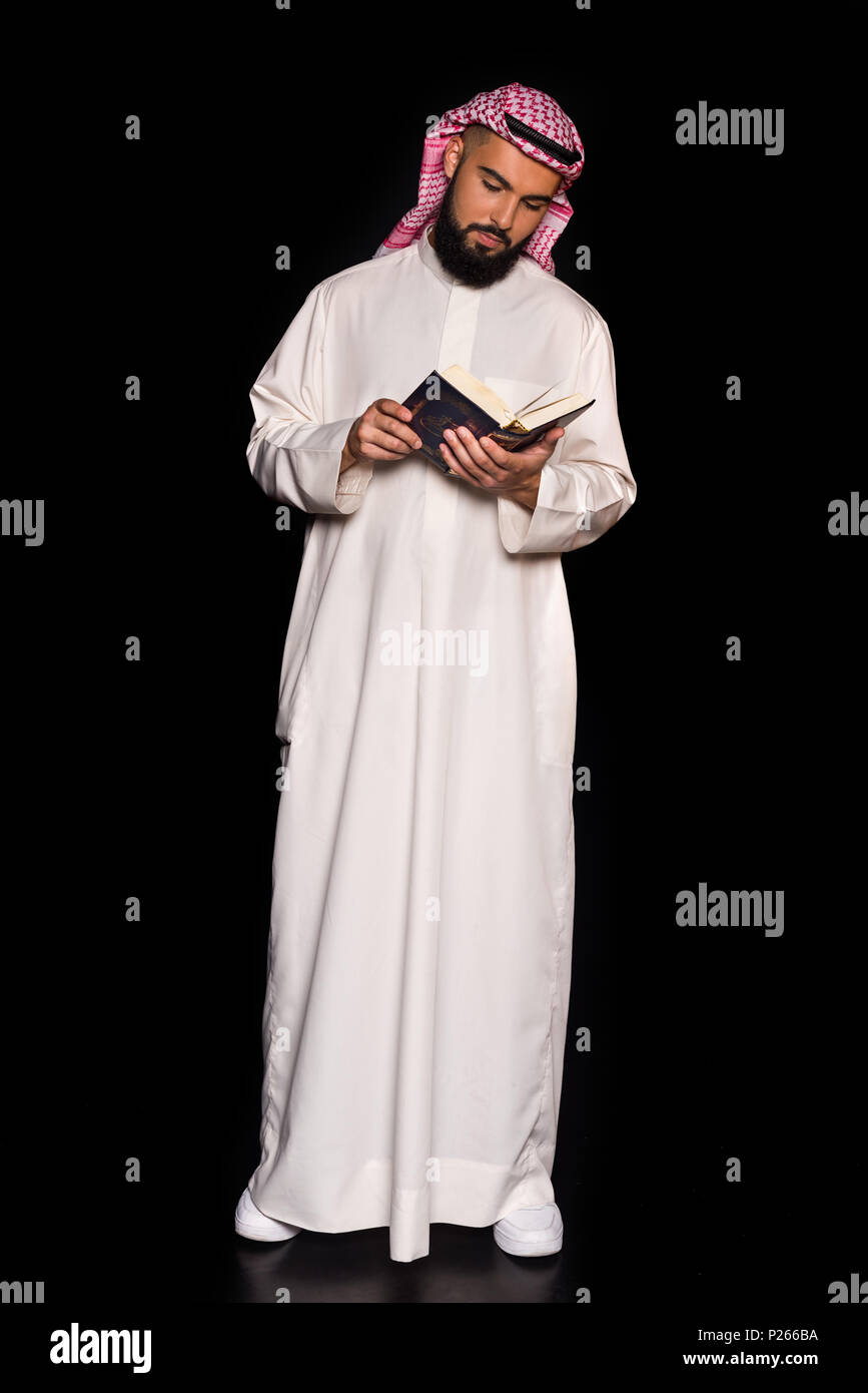 handsome muslim man reading quran isolated on black Stock Photo - Alamy