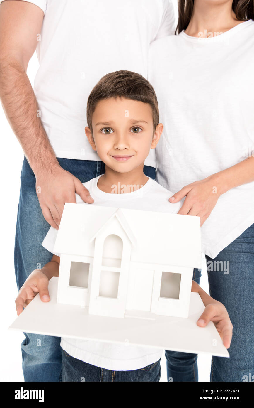 partial view of parents hugging little boy with house model in hands ...