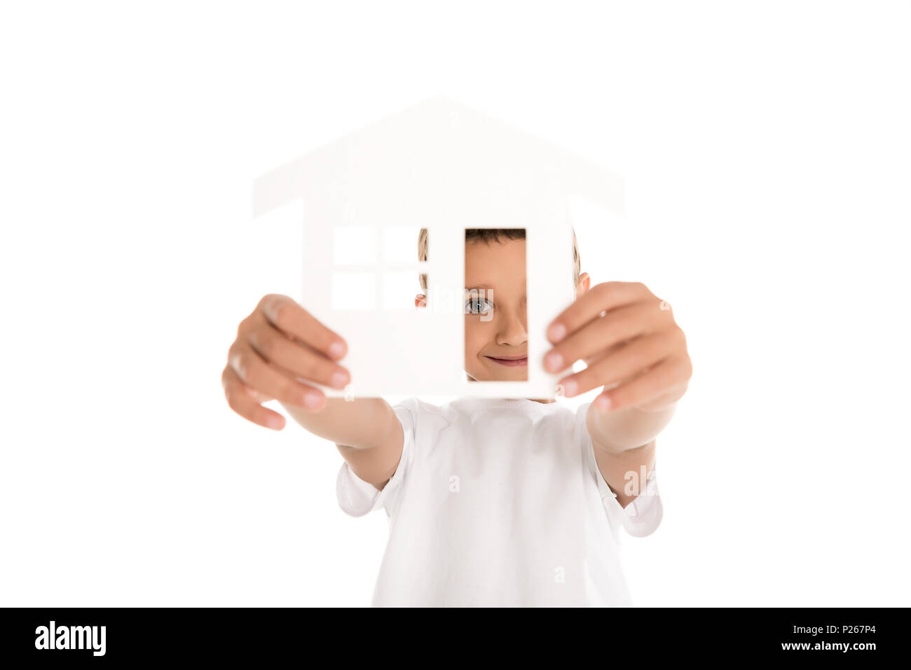 portrait of smiling boy looking at camera through house model isolated ...