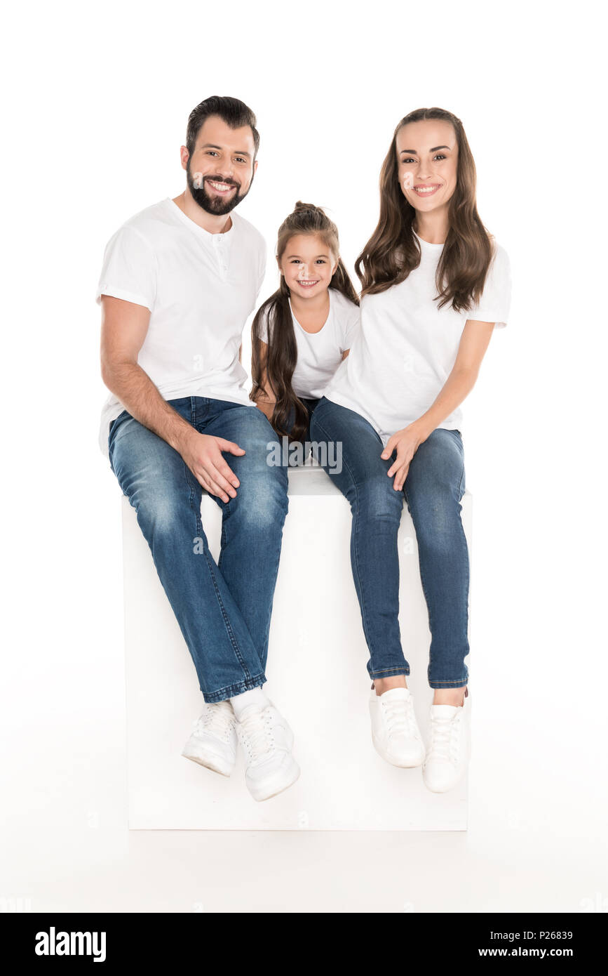 happy parents with daughter sitting on white cube, isolated on white ...