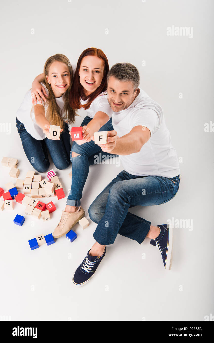 young mother, daughter and father showing alphabet blocks with letters ...