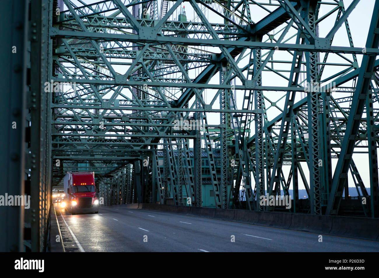 Red big rig semi truck with semi trailer running on arched truss ...