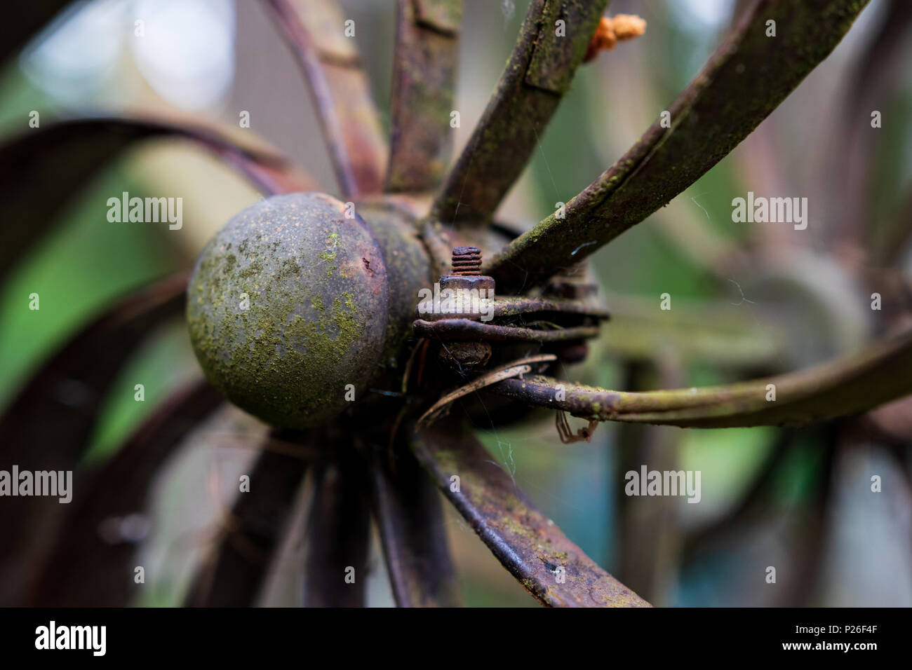 Rusty garden spinner covered in moss and rust Stock Photo - Alamy