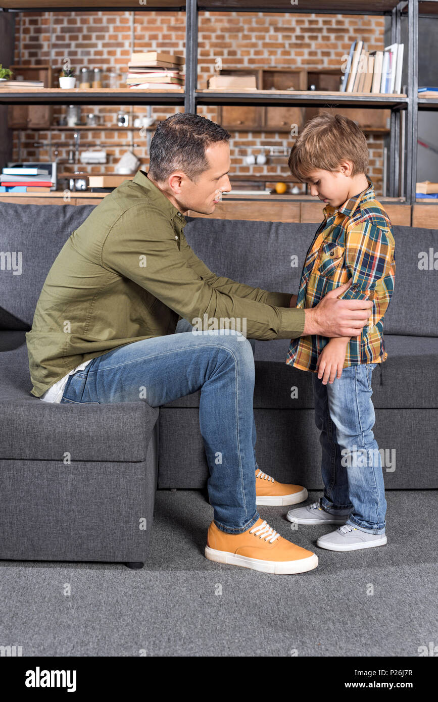 side view of father cheering up upset son at home Stock Photo - Alamy
