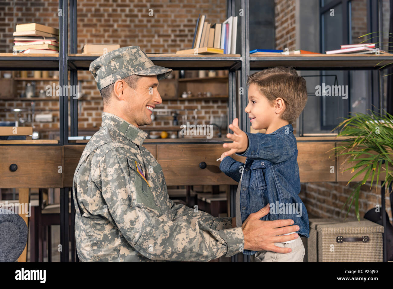 side view of happy boy and father in military uniform at home Stock ...